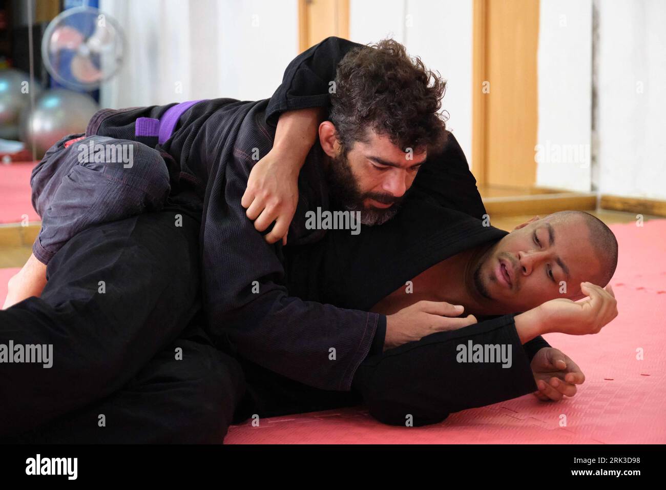 Two men practicing Brazilian Jiu-Jitsu sparring at the Academy Stock ...