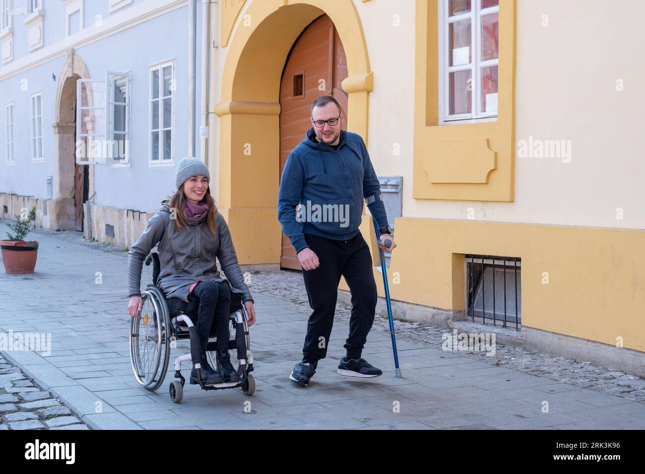 Friends with a disability. Woman in a wheelchair and man with a walking ...
