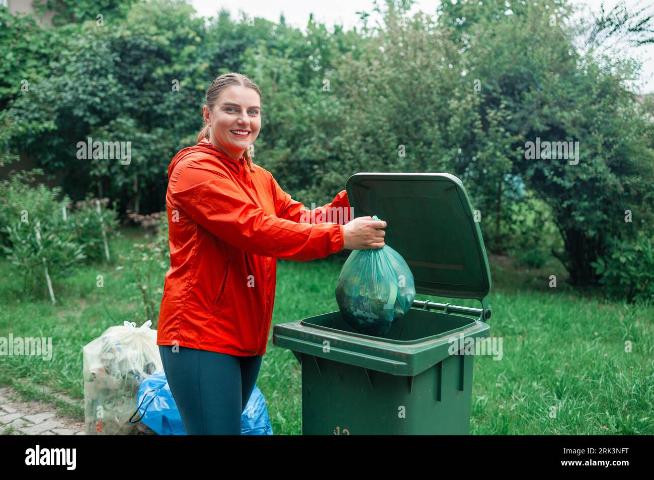 Caucasian woman sorting garbage, throwing a used bag with trash in a ...