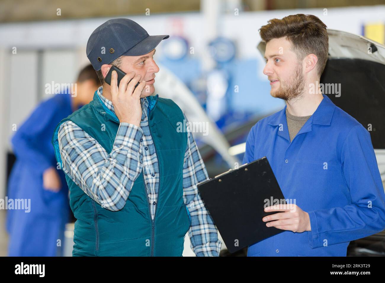 male mechanic in a garage with apprentice Stock Photo - Alamy