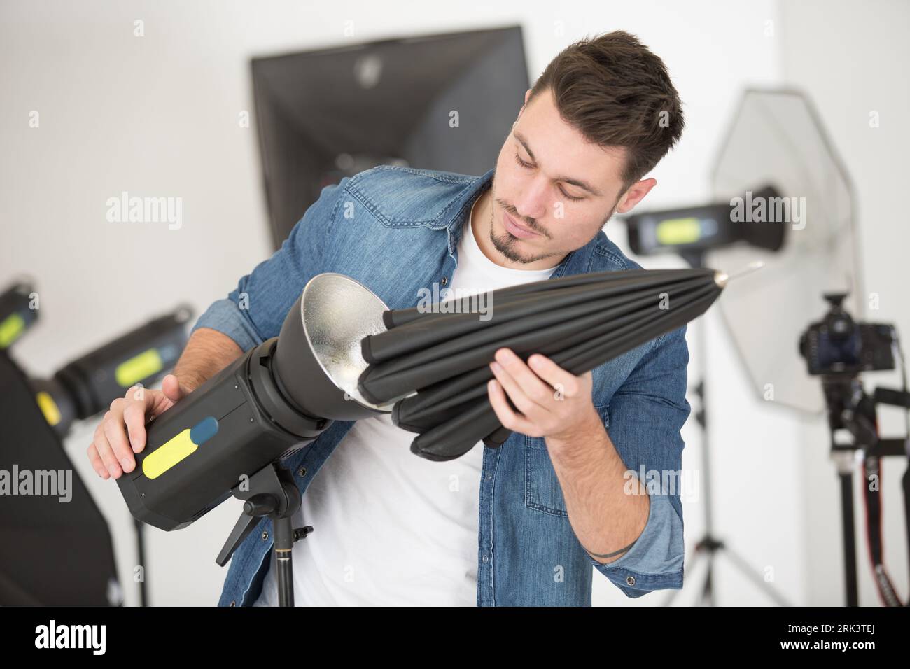 young male photographer is preparing professional lighting equipment ...