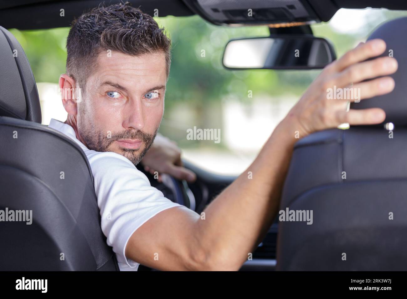 male driver looking back between seats to reverse Stock Photo - Alamy