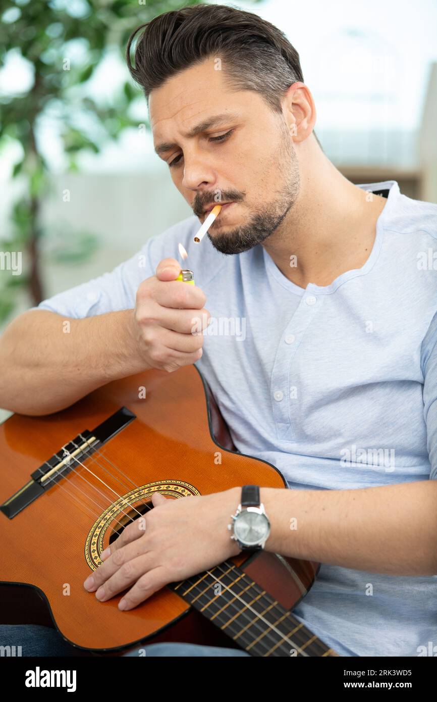 male guitarist lighting a cigarette Stock Photo - Alamy
