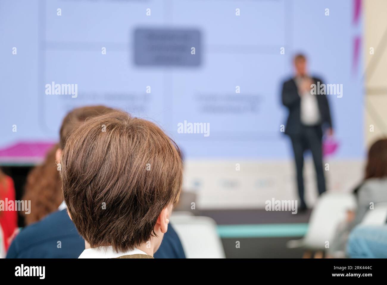 Back view of anonymous gray haired male in audience listening to ...