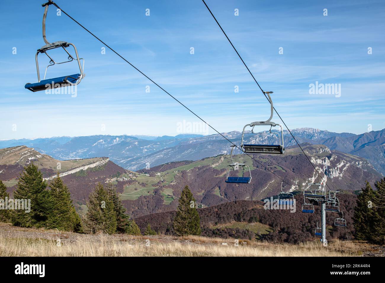 The empty ski lift above a rocky hillside landscape with rocky peaks in ...