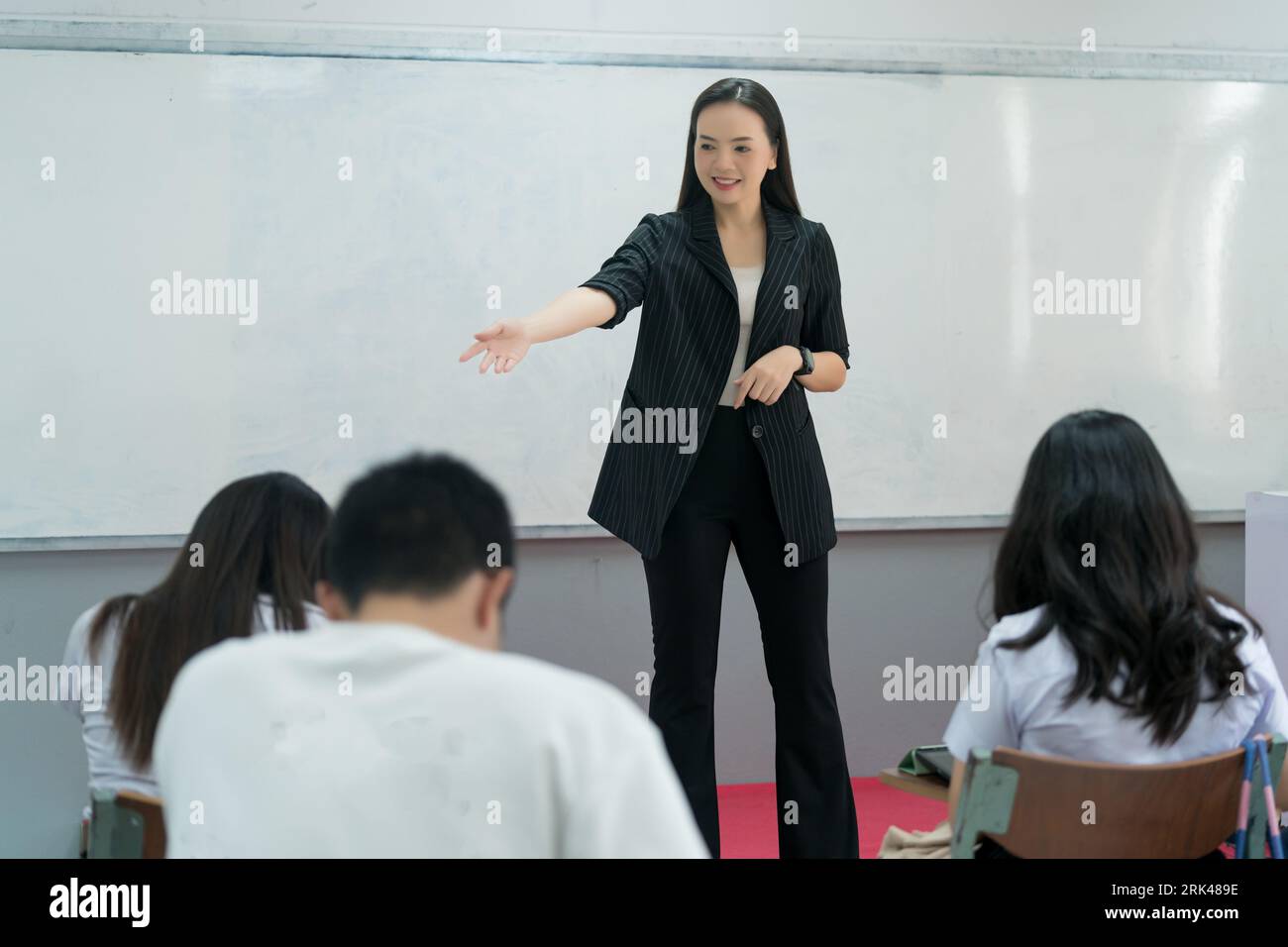 A female student stands in front of a classroom of her peers delivering ...
