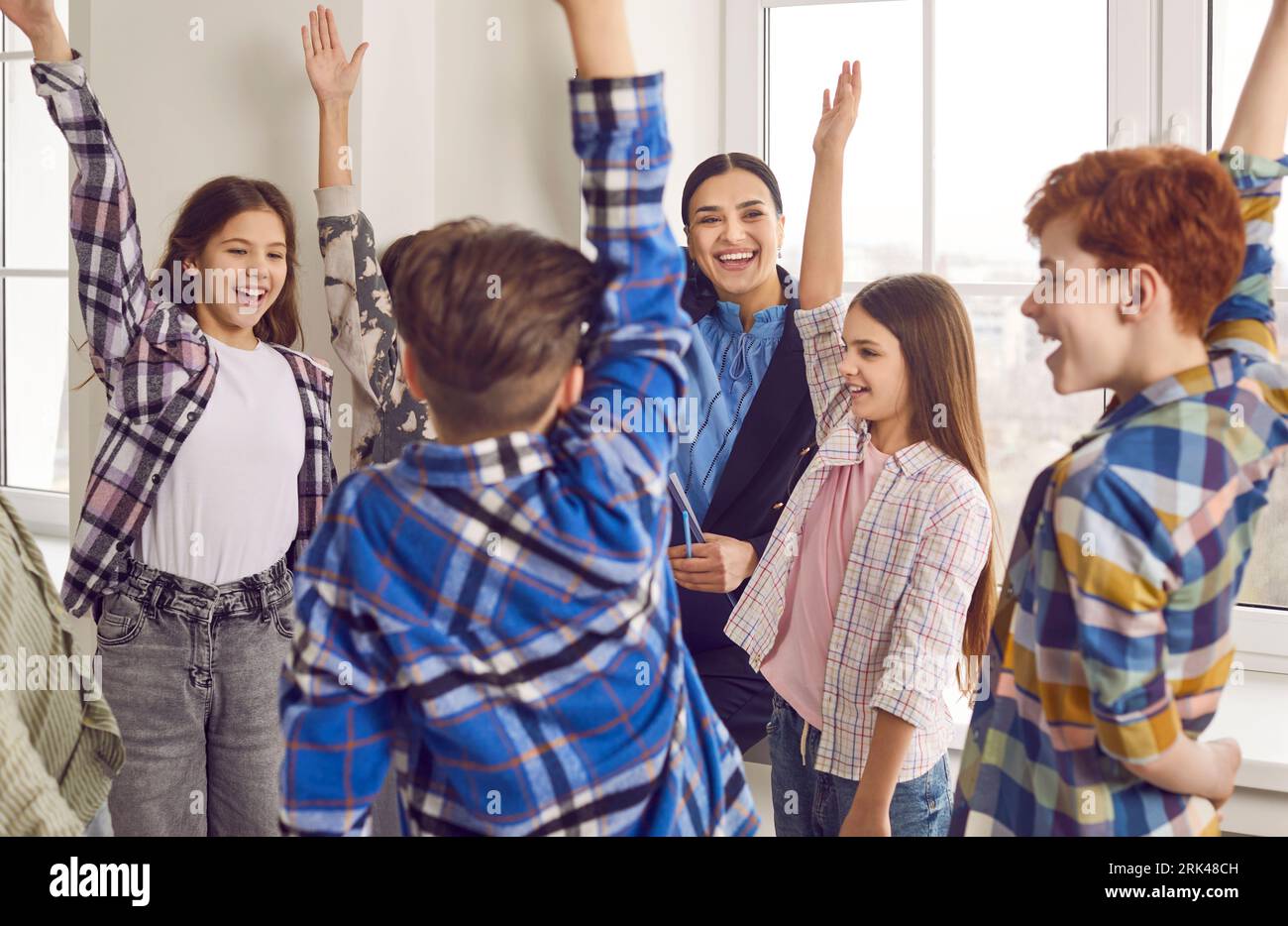 Group of happy junior school students raising hands together while ...