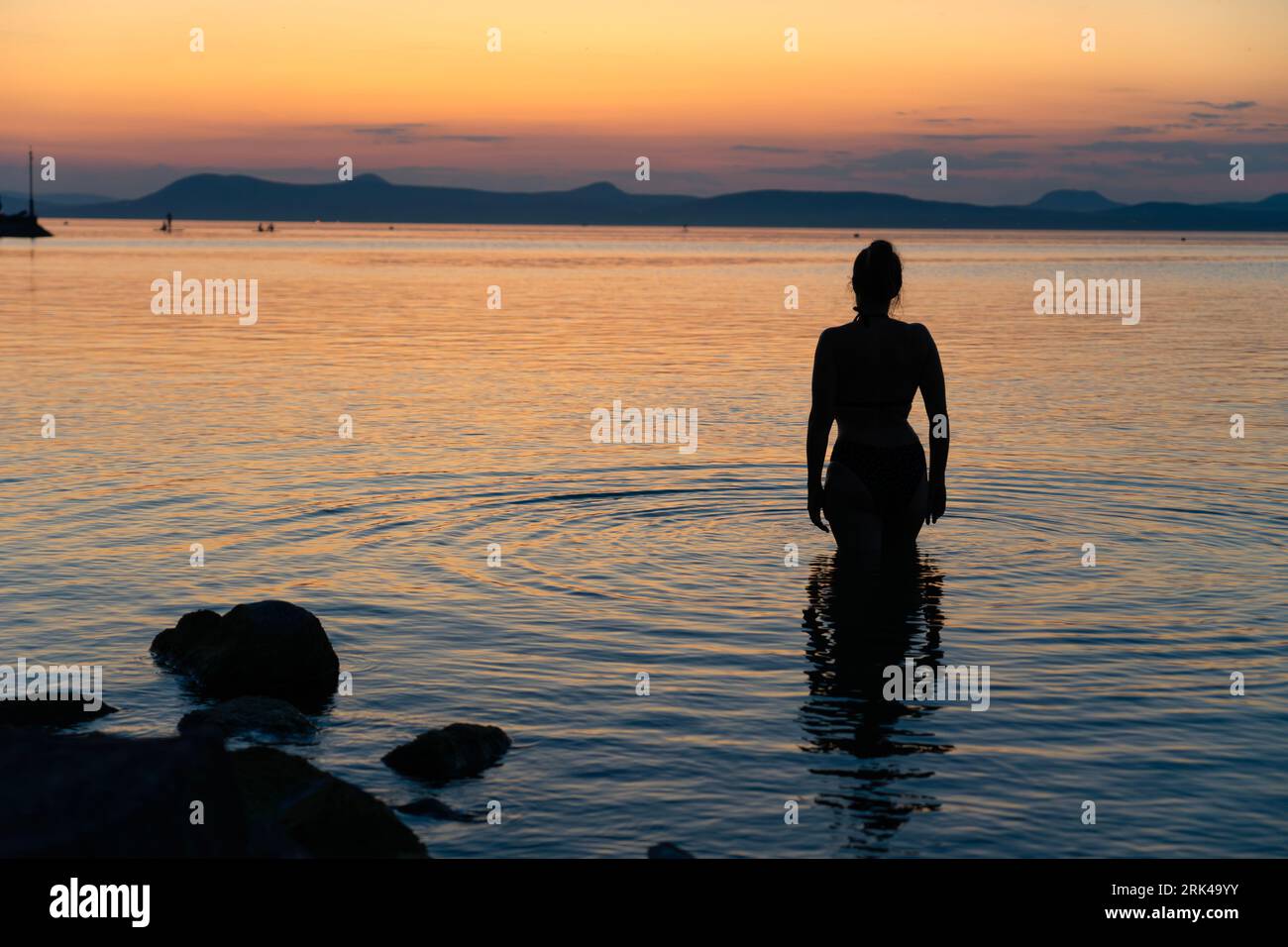 sunset at Lake Balaton with silhouette of night bathing woman and the ...