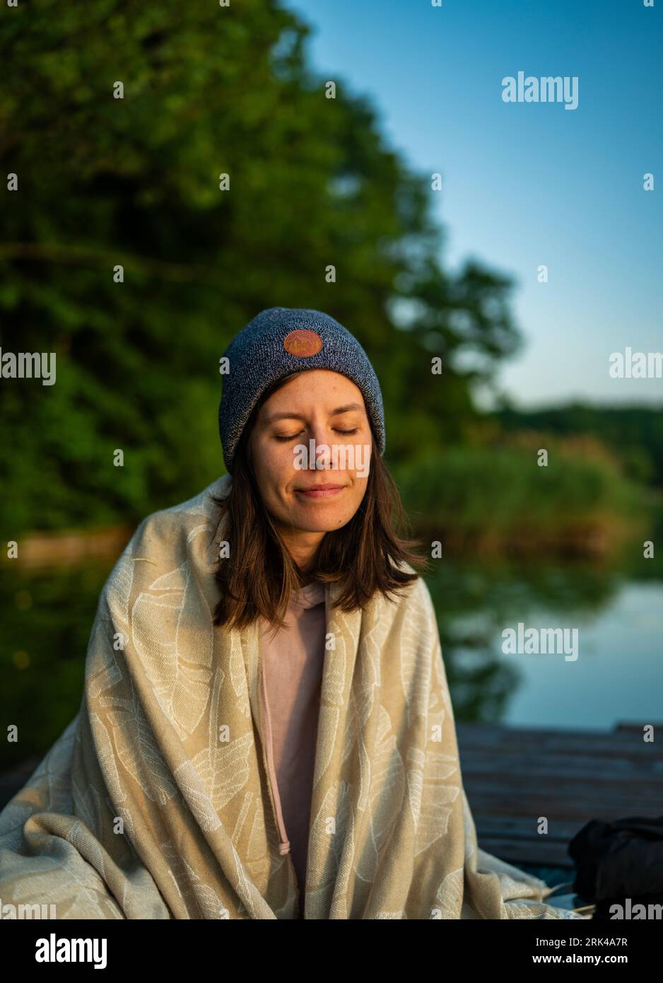 A Caucasian female with a tranquil expression sits in a forest, with a ...