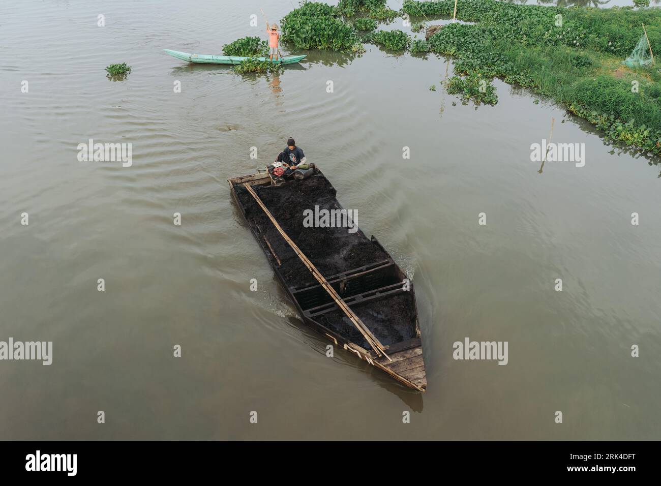 A miner transport peat soil by boat on Rawa Pening lake in Semarang ...