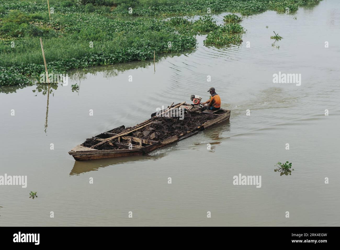 A miner transport peat soil by boat on Rawa Pening lake in Semarang ...