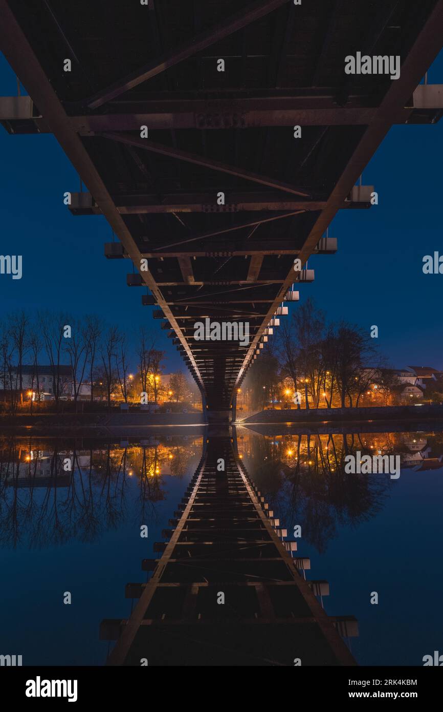 An illuminated underpass bridge in a modern city by a riverbank at ...