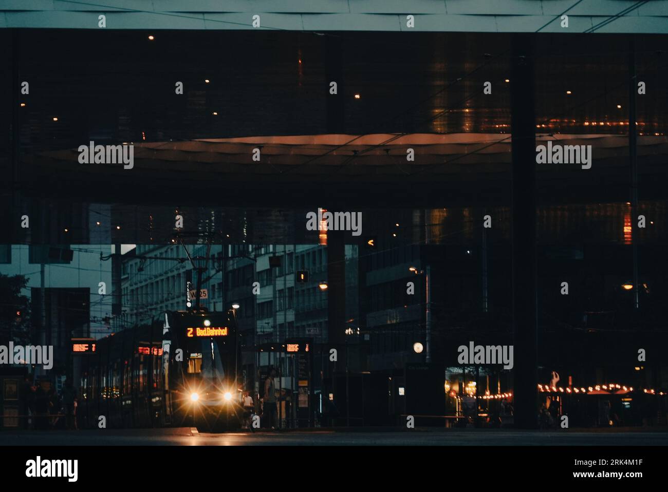 A bus driving in the city at night, its headlights illuminating the ...