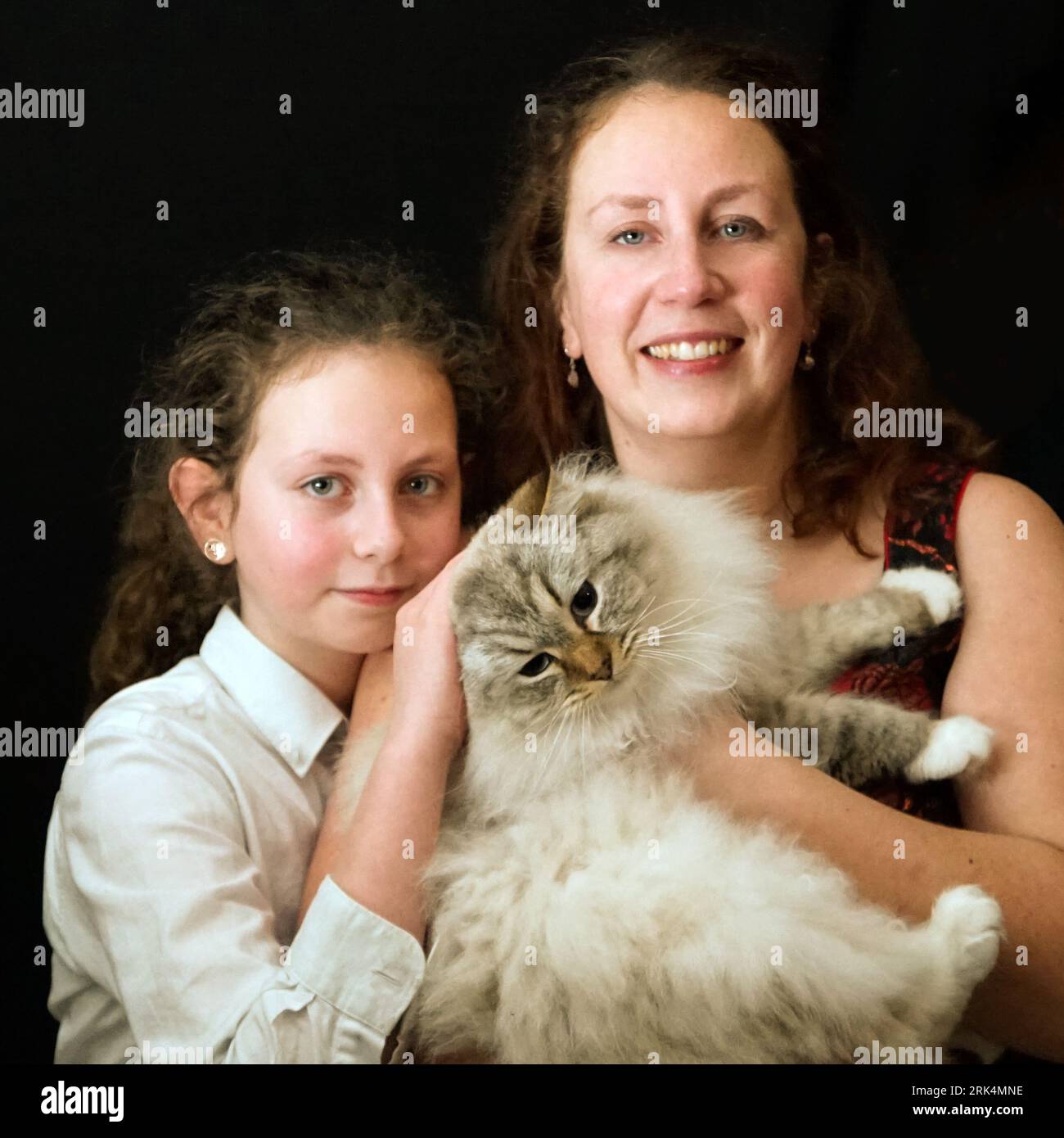 Mother and daughter posing with their ragdoll cat. Three beautiful ...