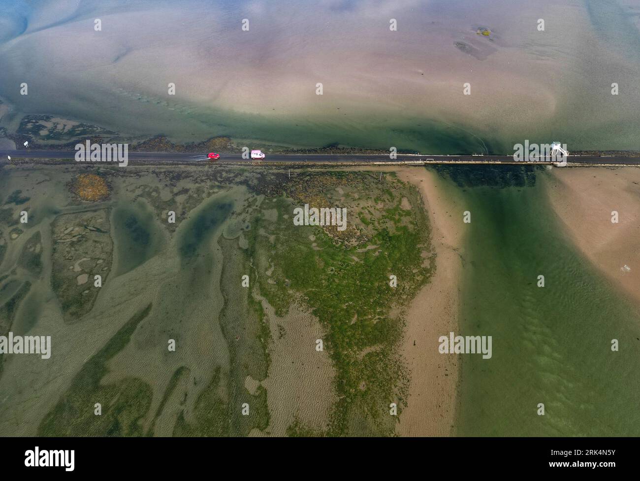 Vehicles travel along Holy Island causeway in Northumberland which ...