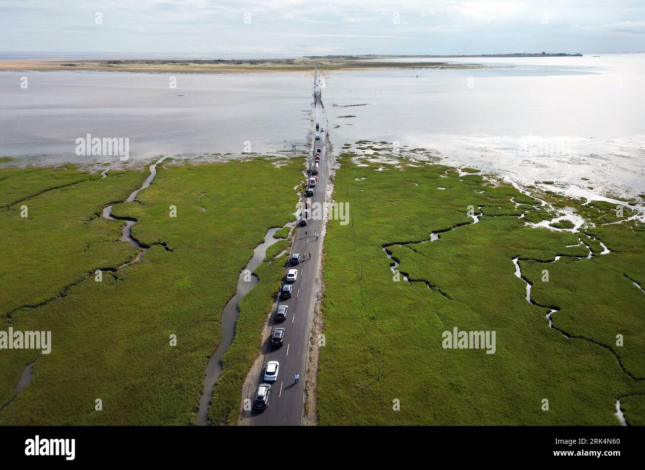 Vehicles travel along Holy Island causeway in Northumberland which ...