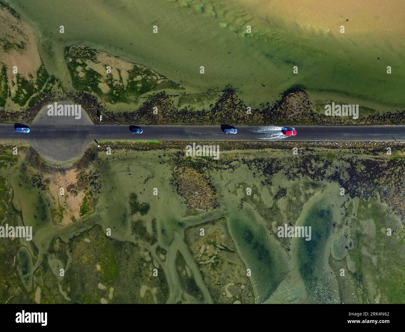 Vehicles travel along Holy Island causeway in Northumberland which ...