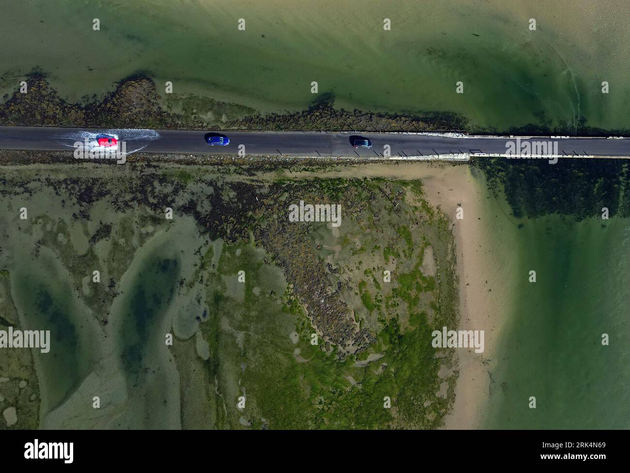 Vehicles travel along Holy Island causeway in Northumberland which ...