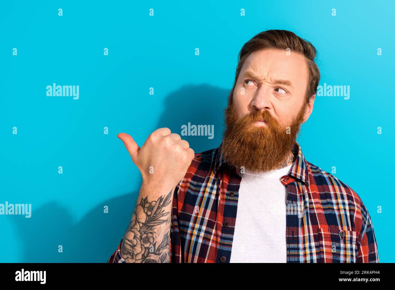 Portrait of thoughtful hipster man tattoo hand directing finger empty ...