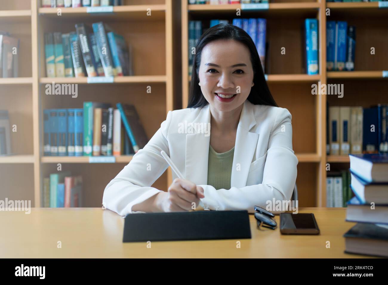 A Southeast Asian female lecturer sits at a small table, working at the ...