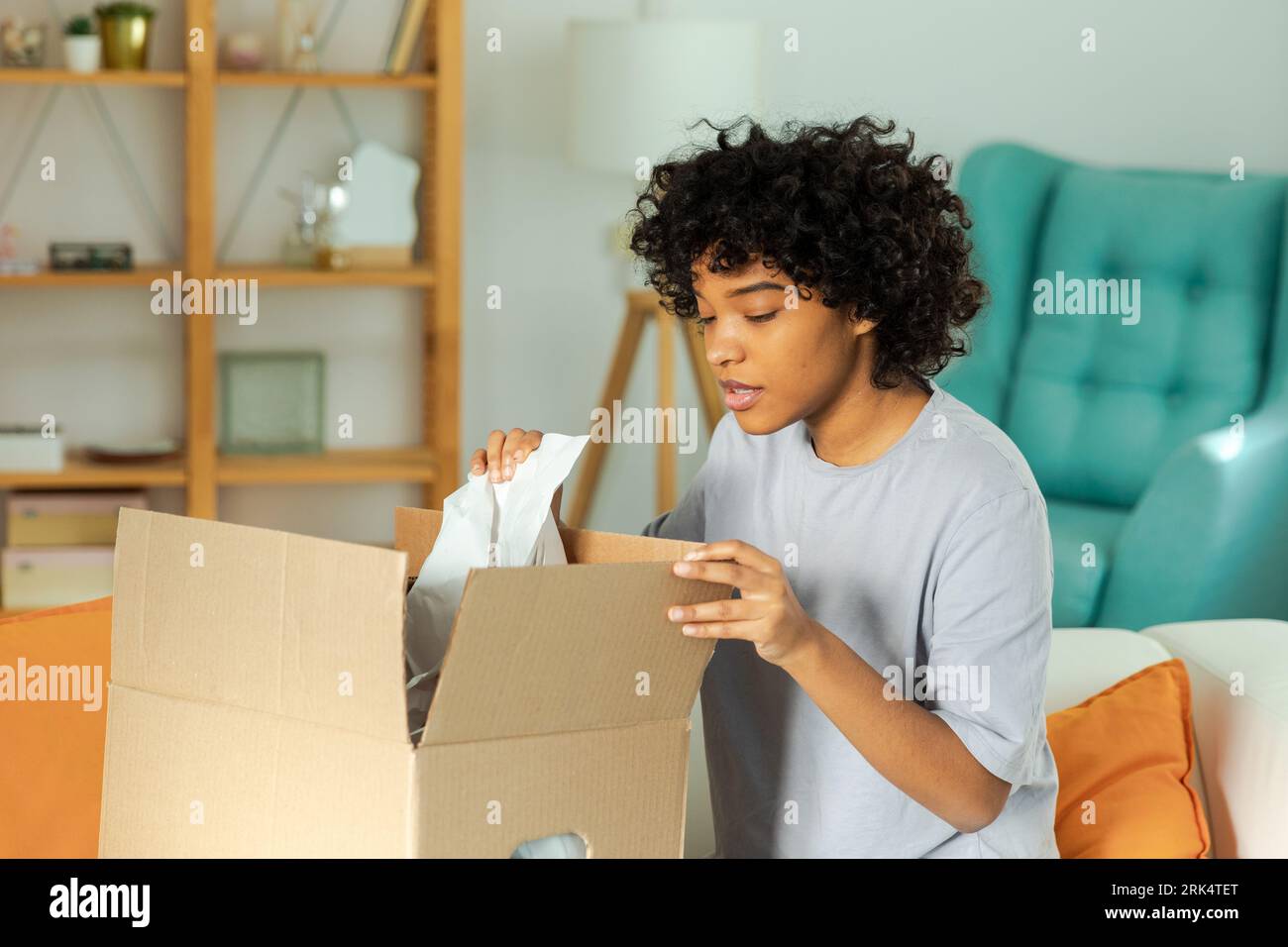African girl unpacking delivery looking in box. Happy woman opening ...