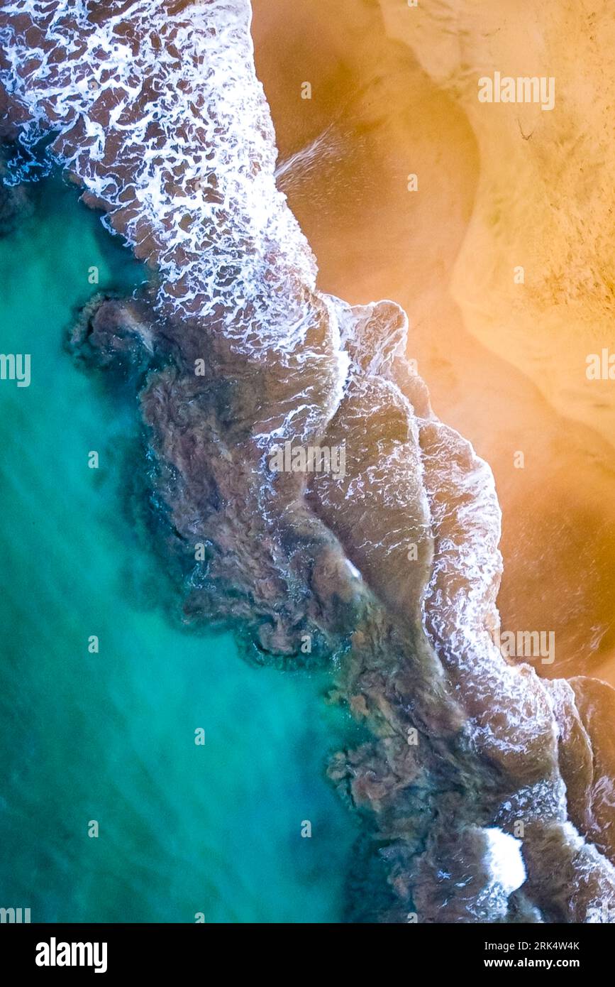 An aerial view of a picturesque beach surrounded by crystal blue waves ...