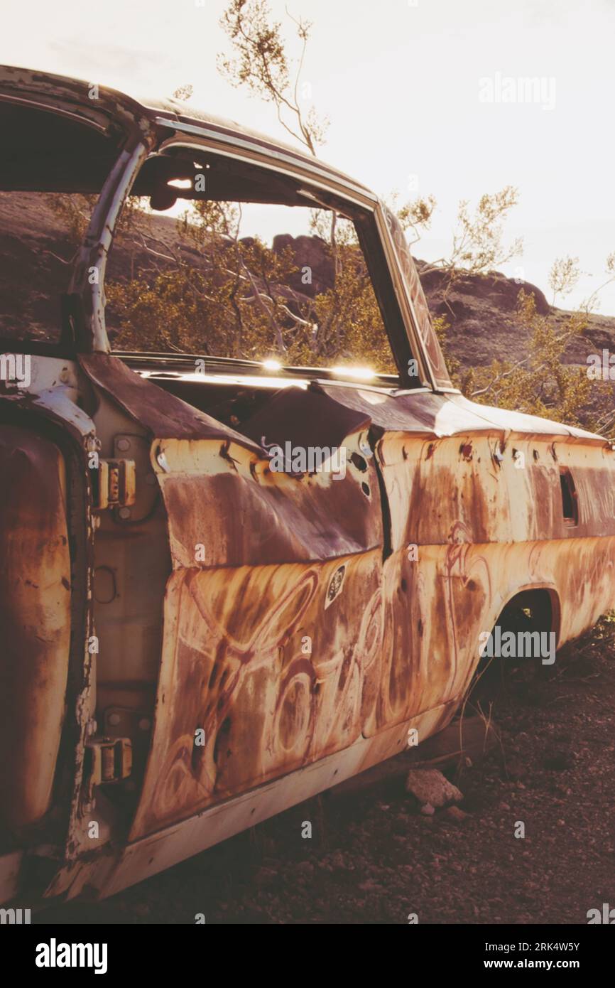 A vintage, abandoned car sits in the middle of a deserted rural ...