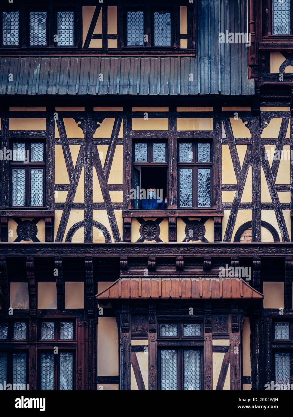 An person standing in a window of an old building, looking out into the ...