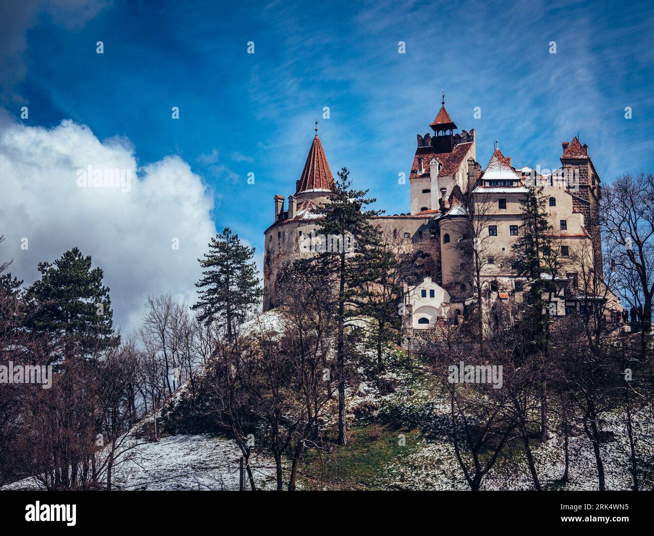 The Bran castle in Romania stands atop a snow-covered hill, framed by a ...