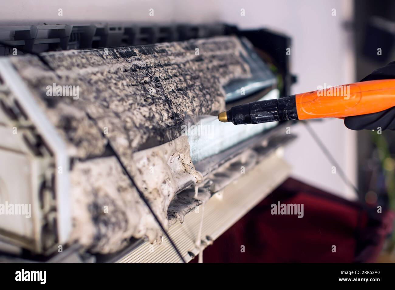 Cleaning the air conditioner by spraying. man washes off a special foam ...