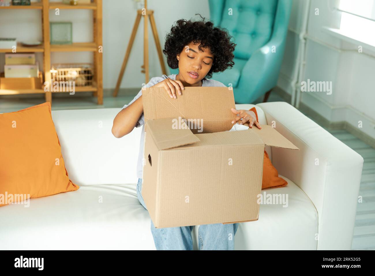 African girl unpacking delivery looking in box. Happy woman opening ...