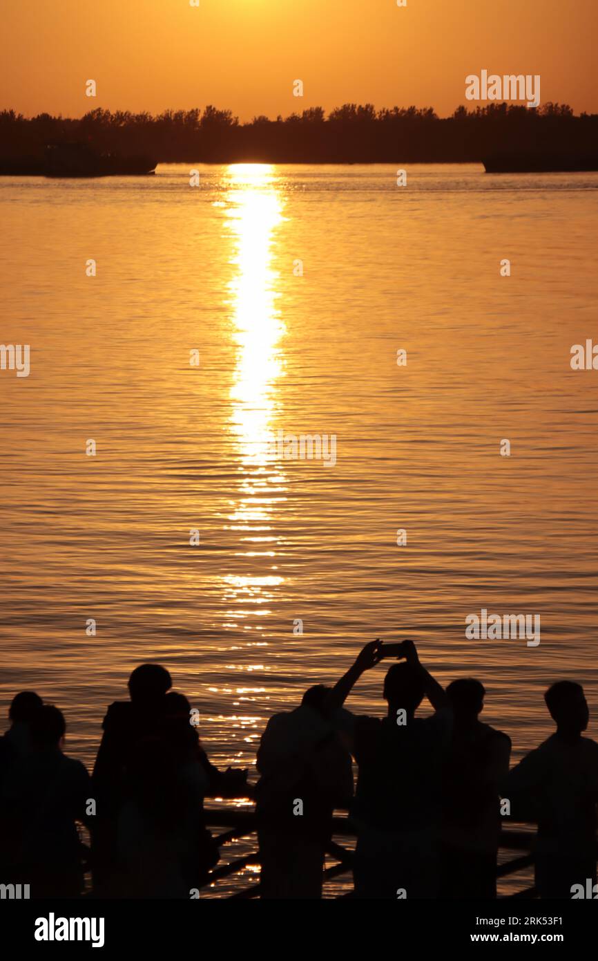 A group of people capturing a stunning sunset landscape with their ...