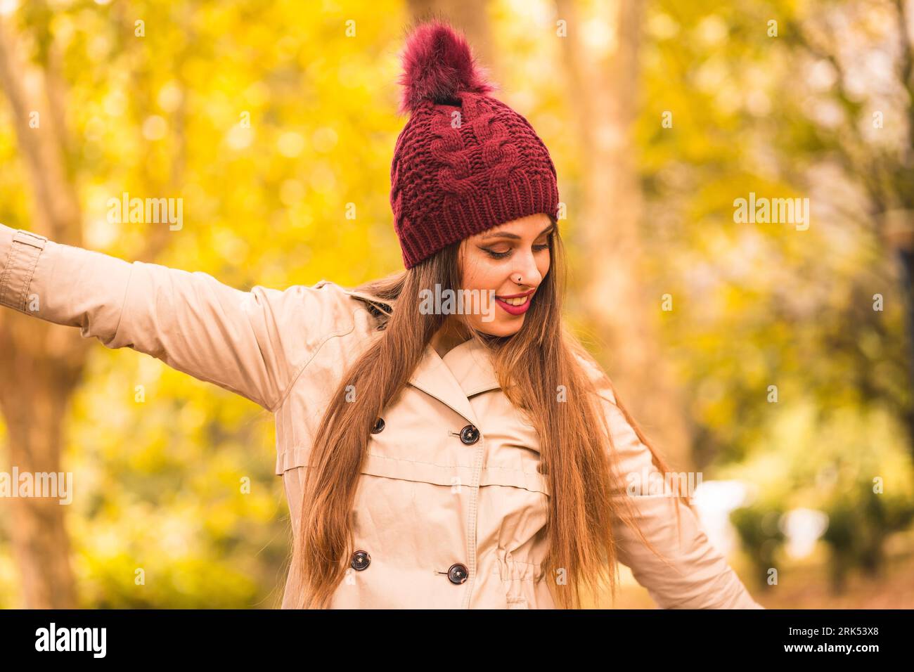 A cheerful young woman in fall apparel joyfully strolling through a ...
