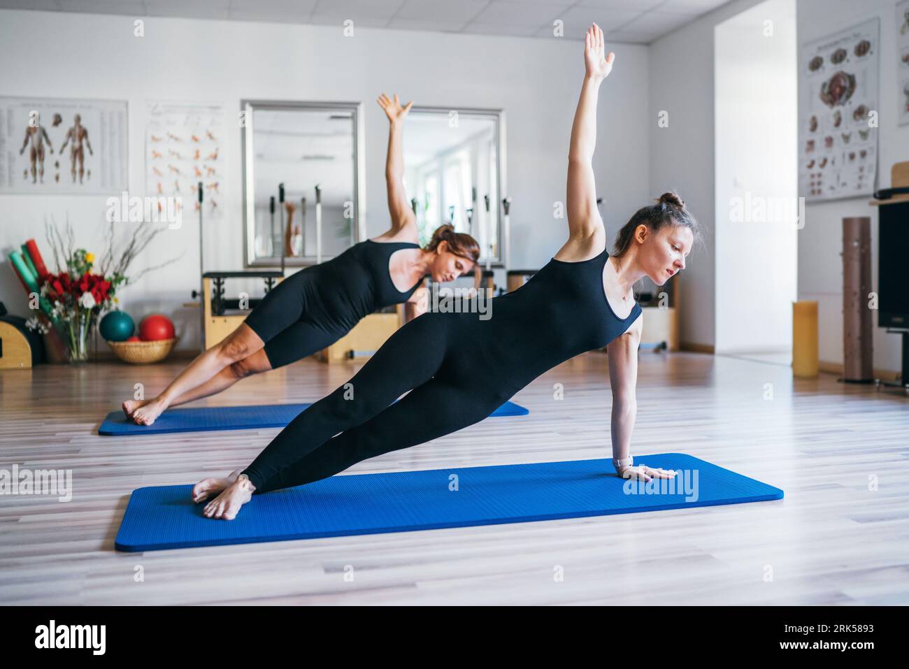 Two young females doing side plank with raised arm static strengthening ...