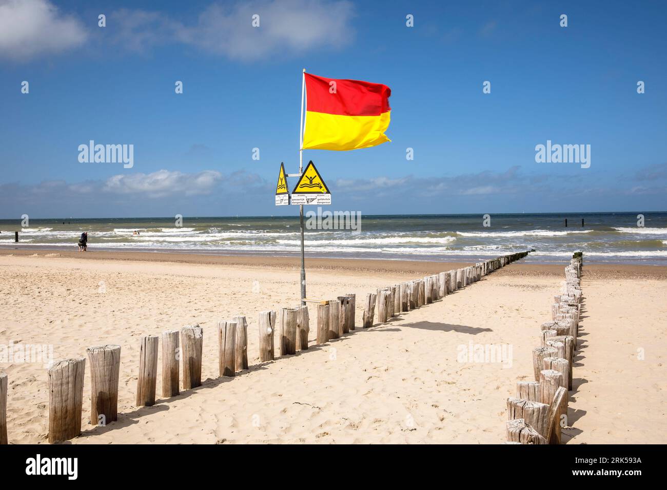 flag and signs warn swimmers of groynes in the water, the beach in ...