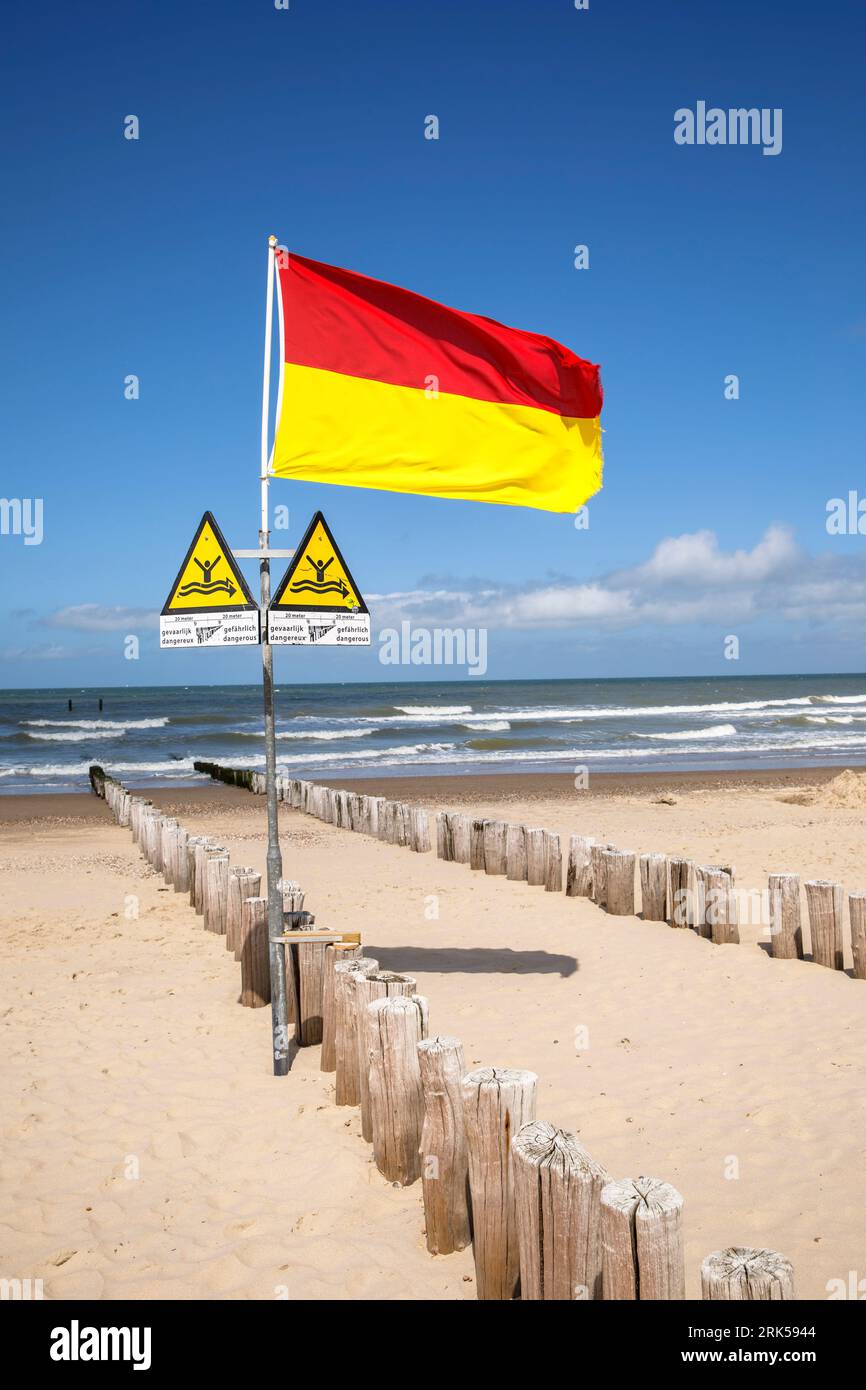 flag and signs warn swimmers of groynes in the water, the beach in ...