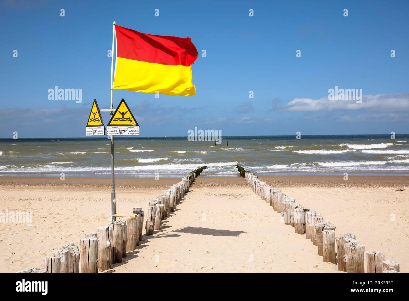 flag and signs warn swimmers of groynes in the water, the beach in ...