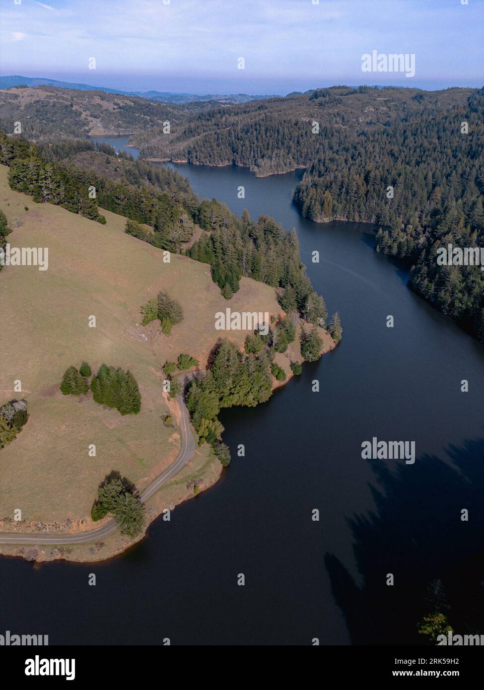 An aerial view of a vast lake surrounded by lush green forest, with a ...