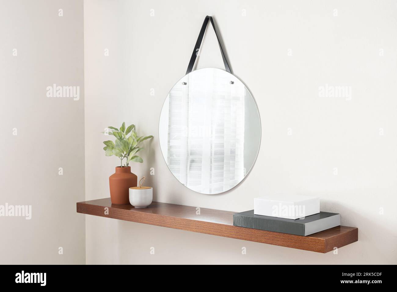 A stylishly designed wooden shelf presented with a decorative mirror ...