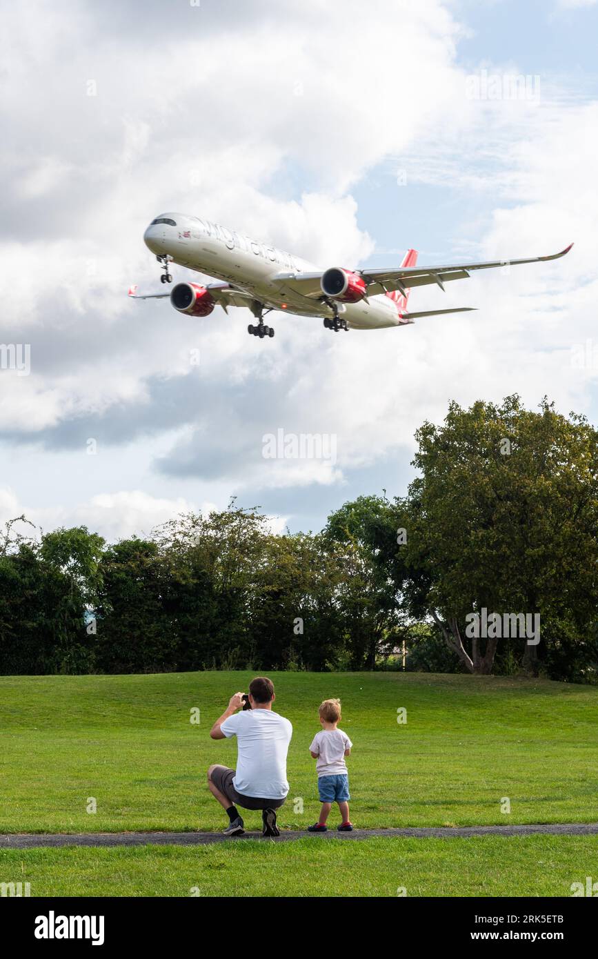Father and son (assumed) watching a jet airliner plane on finals to ...