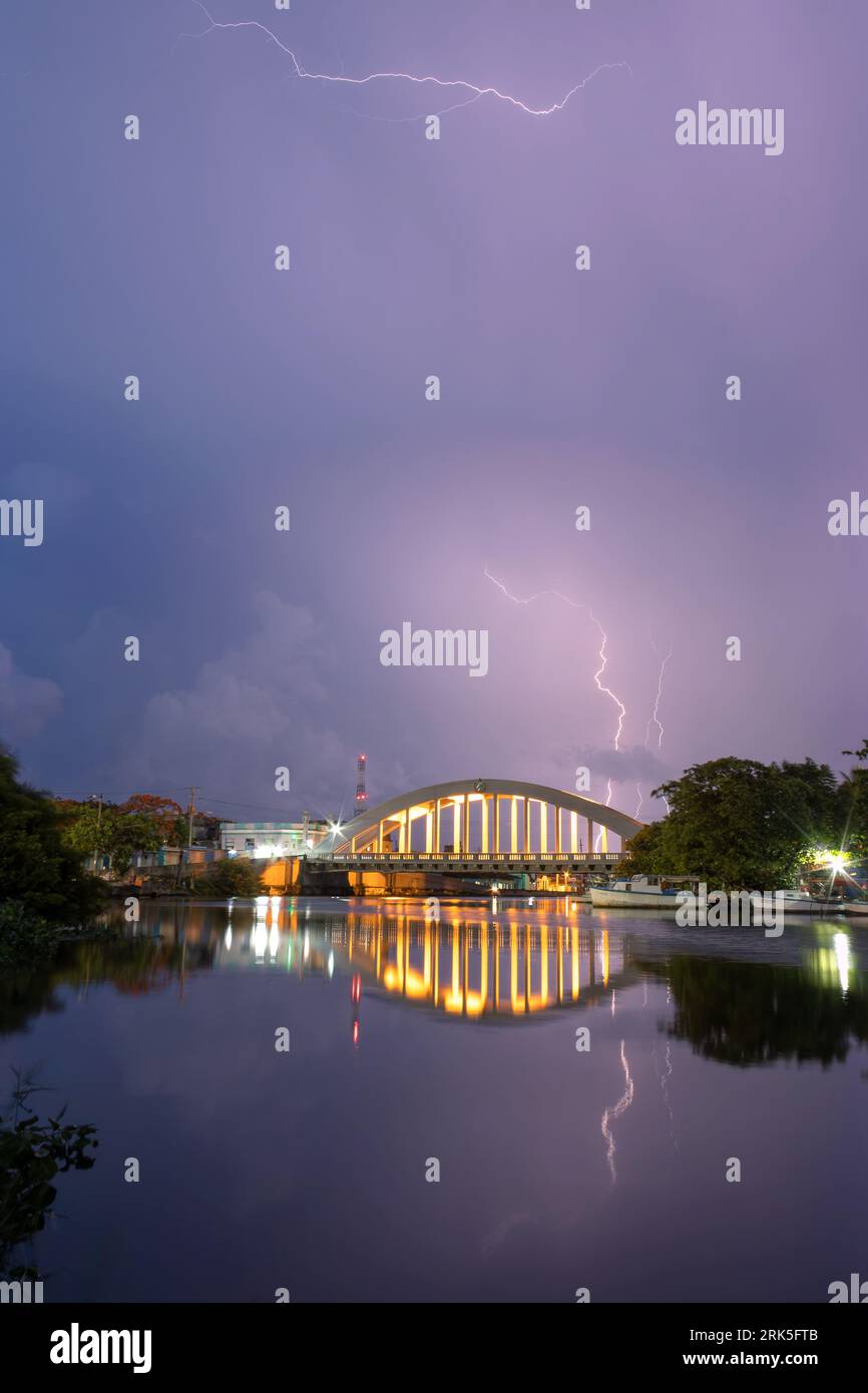 A vertical shot of lightning striking over the illuminated Bridge of ...