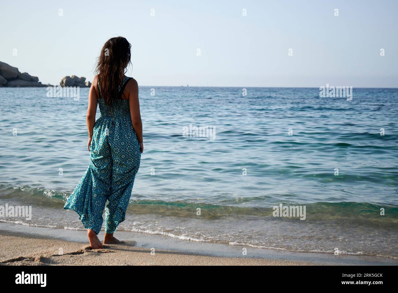 A woman leisurely strolling on a picturesque beach, with the crystal ...