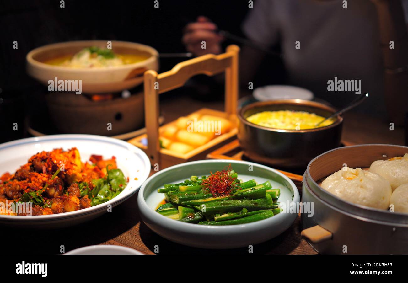 A variety of traditional Chinese dishes are displayed on a table in a ...
