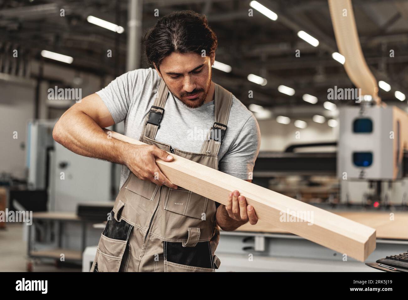 Young carpenter man looking and choosing wood plank at workshop in ...