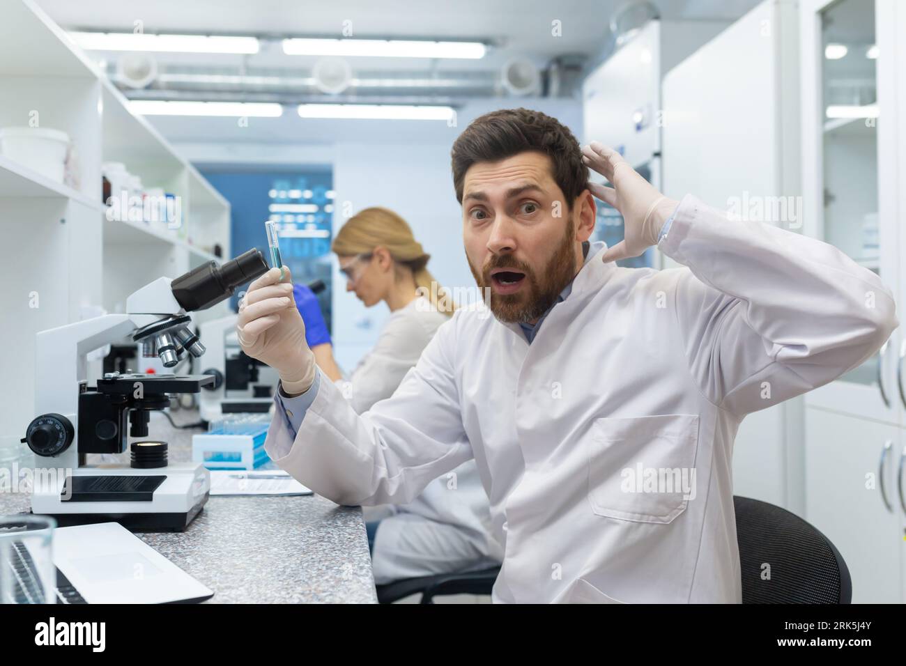 Portrait of a shocked young male scientist sitting in a laboratory ...