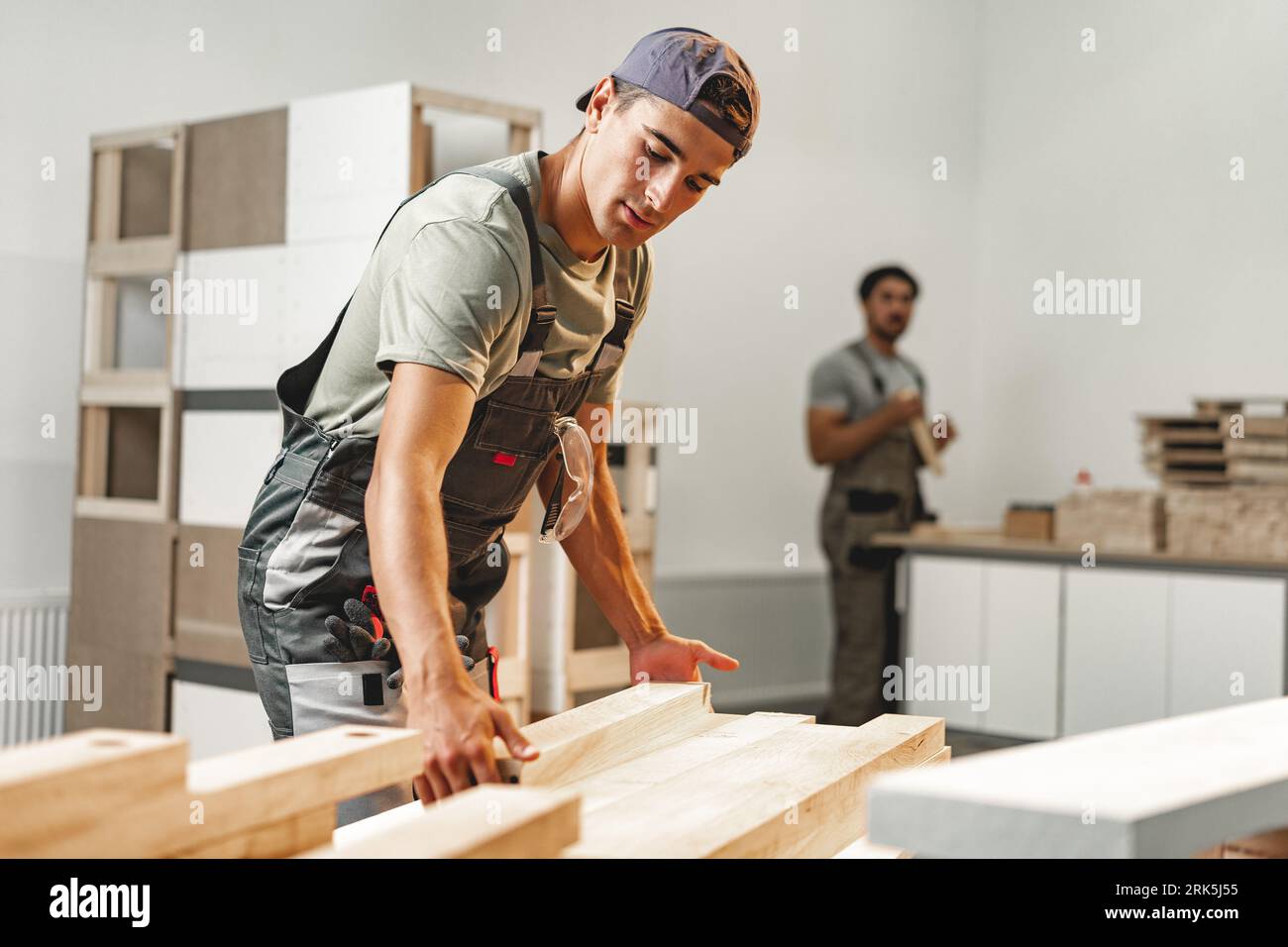 Young carpenter man looking and choosing wood plank at workshop in ...