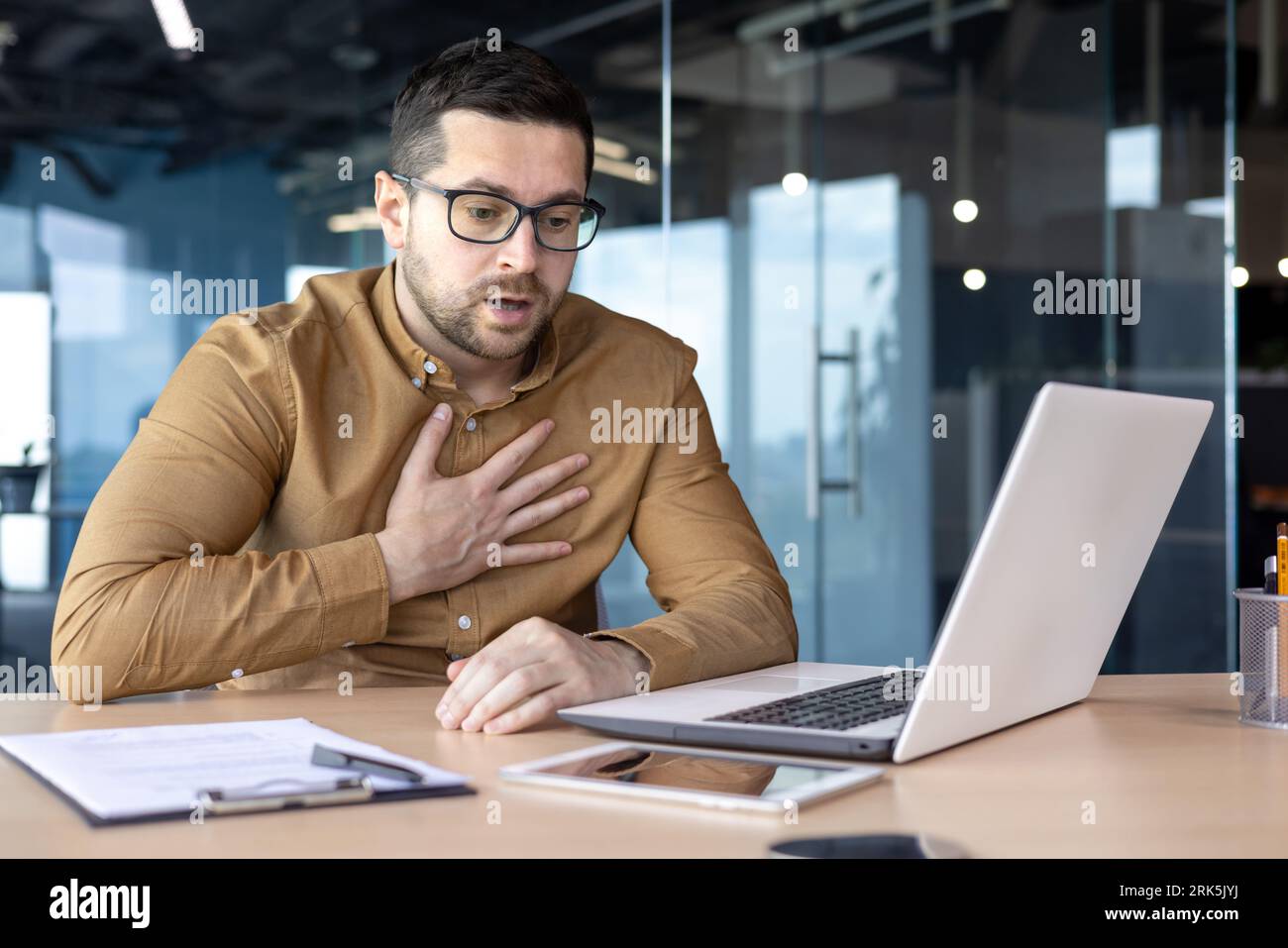 Panic attack in the workplace. A young male office worker sits at a ...