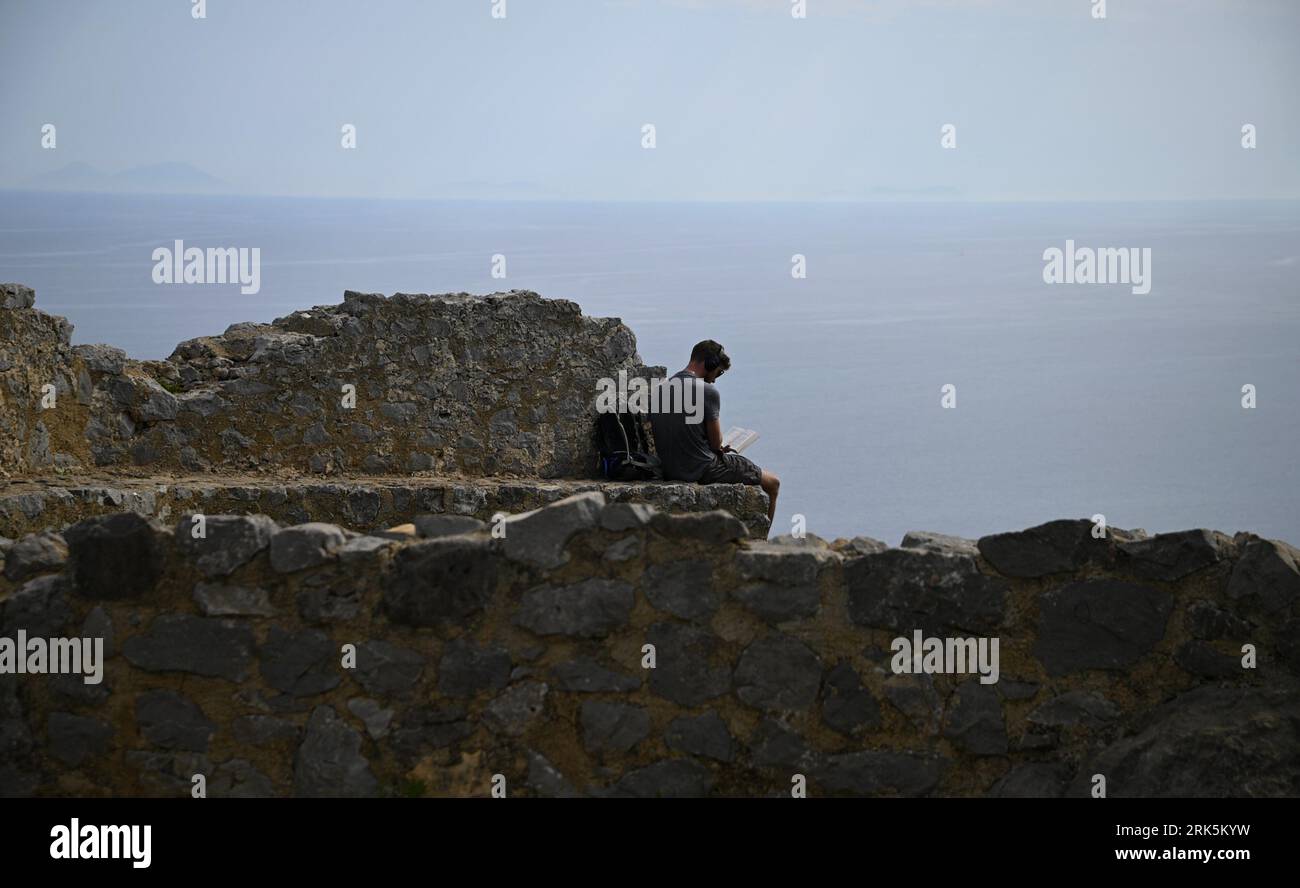 Landscape with a young man sitting on the ancient fortified walls of ...
