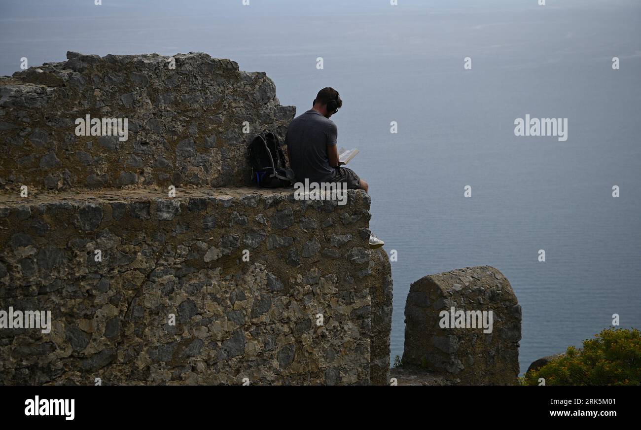 Landscape with a young man sitting on the ancient fortified walls of ...