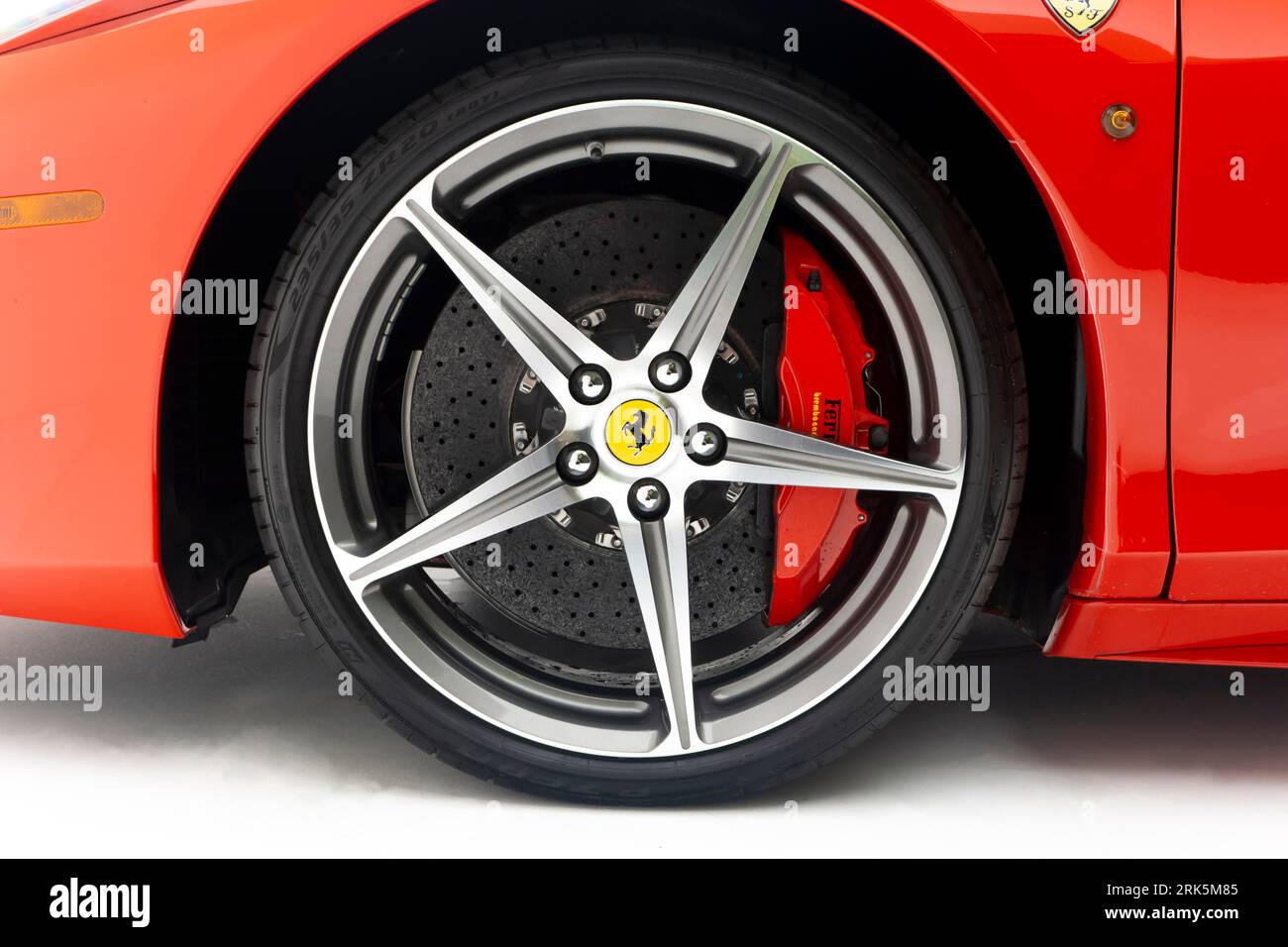 A closeup of a vibrant red Ferrari wheel isolated on white background ...